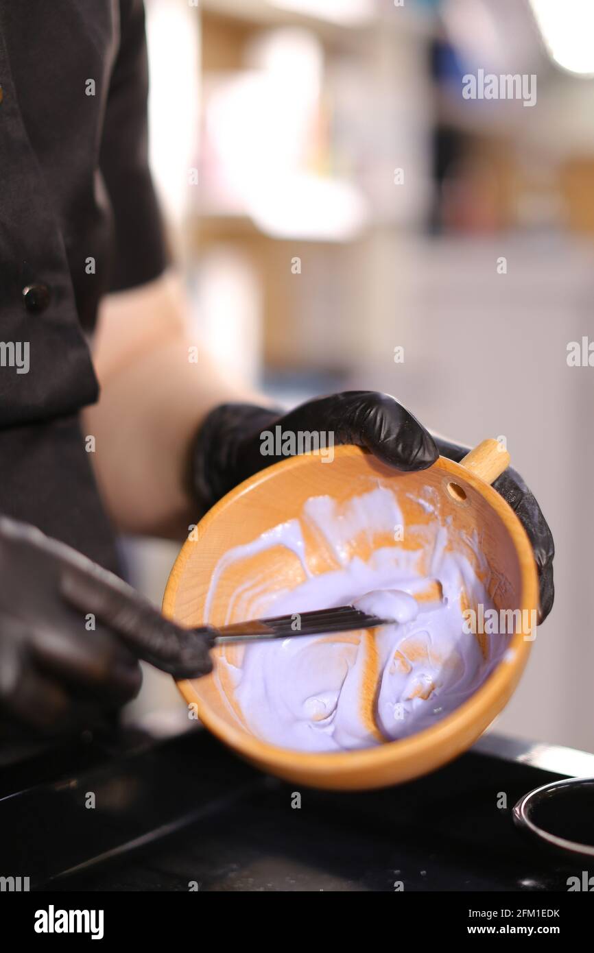 Professional female hairdresser preparing color to female customer at ...