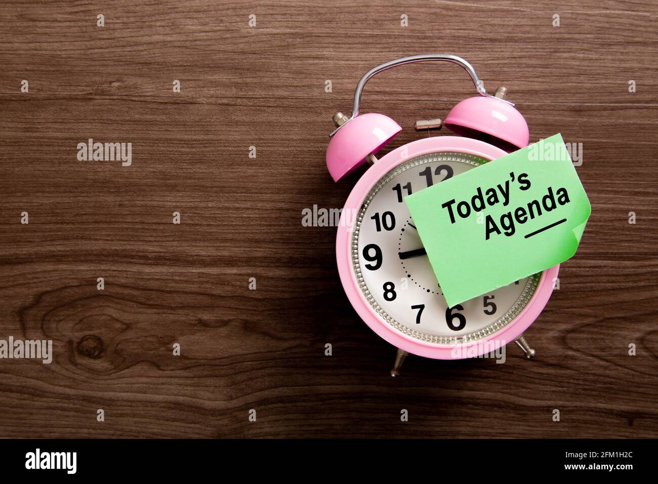 Alarm clock and sticky note written with Today's Agenda on wooden ...