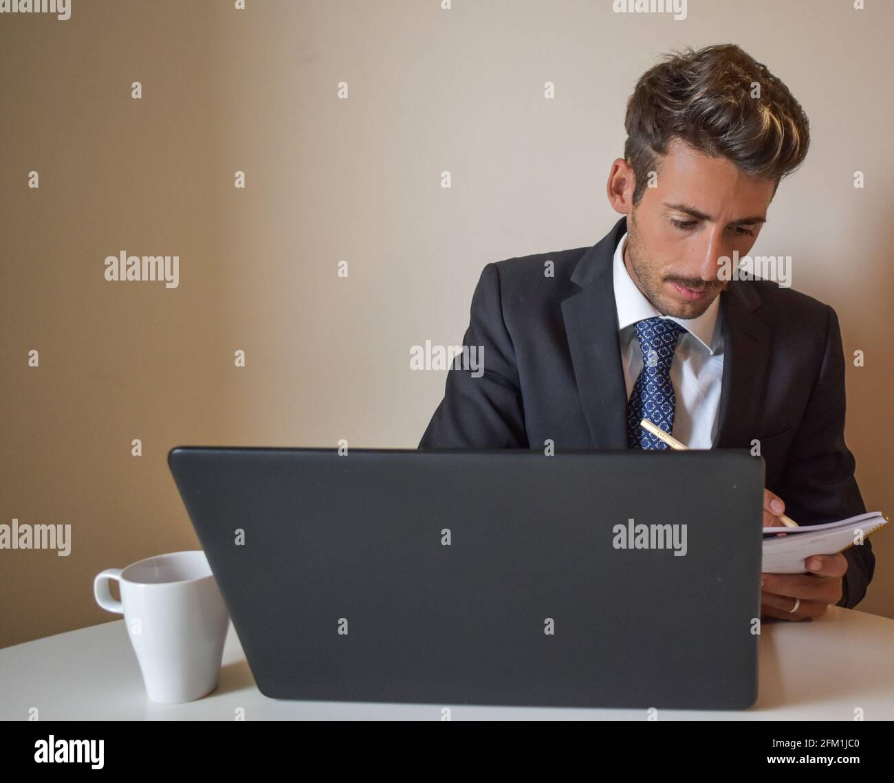 Closeup of a young Spanish businessman in an elegant suit working and ...