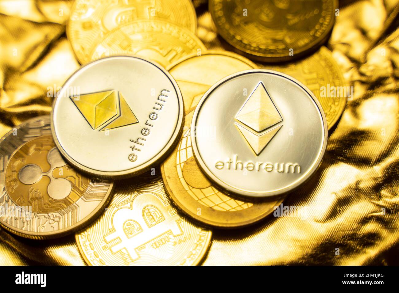Gold ethereum coins on a golden background among another crypto coins ...