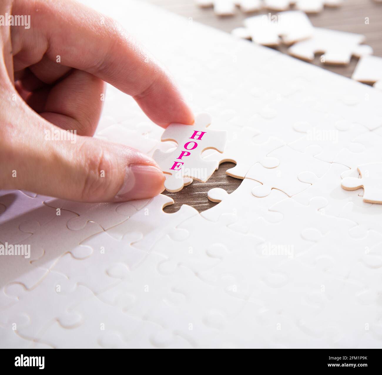 Hand putting the a last piece of white jigsaw puzzle with the word of ...