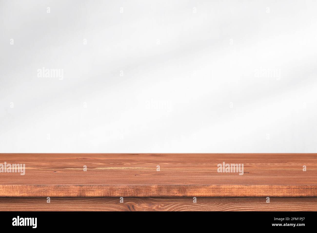 Long wooden table in front of wall with soft light. Empty desk, shelf ...