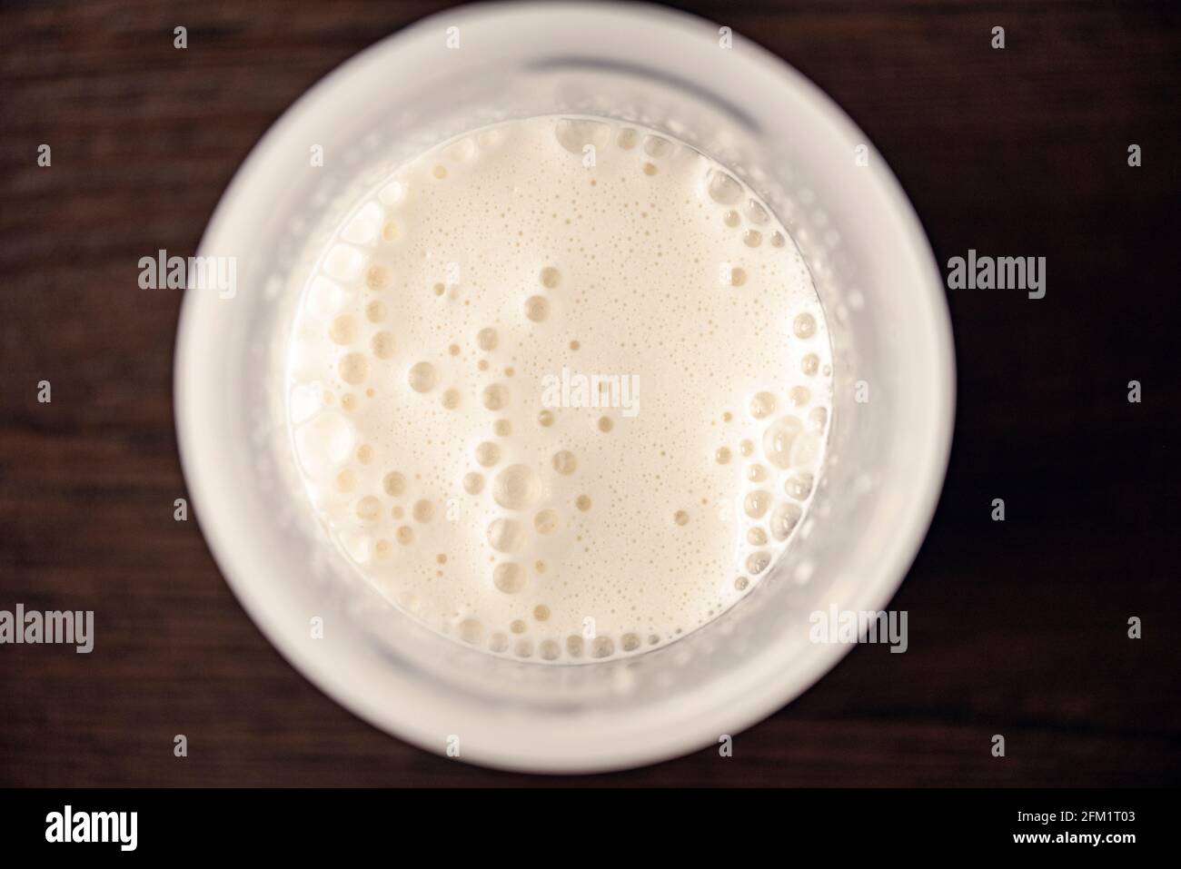 Top view of a glass with vanilla milkshake, frothy cocktail with foam ...