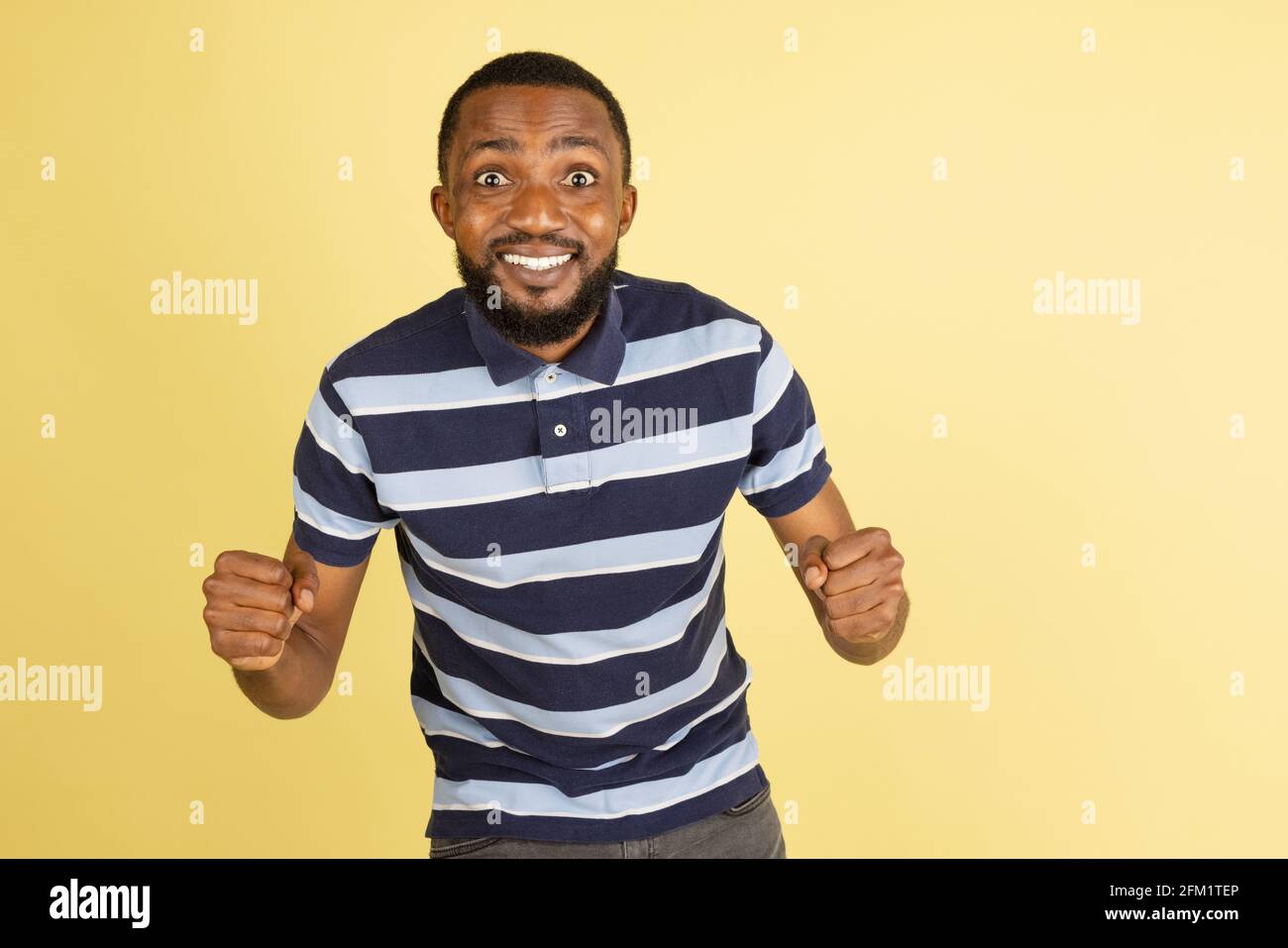One African young man posing isolated over yellow studio background ...