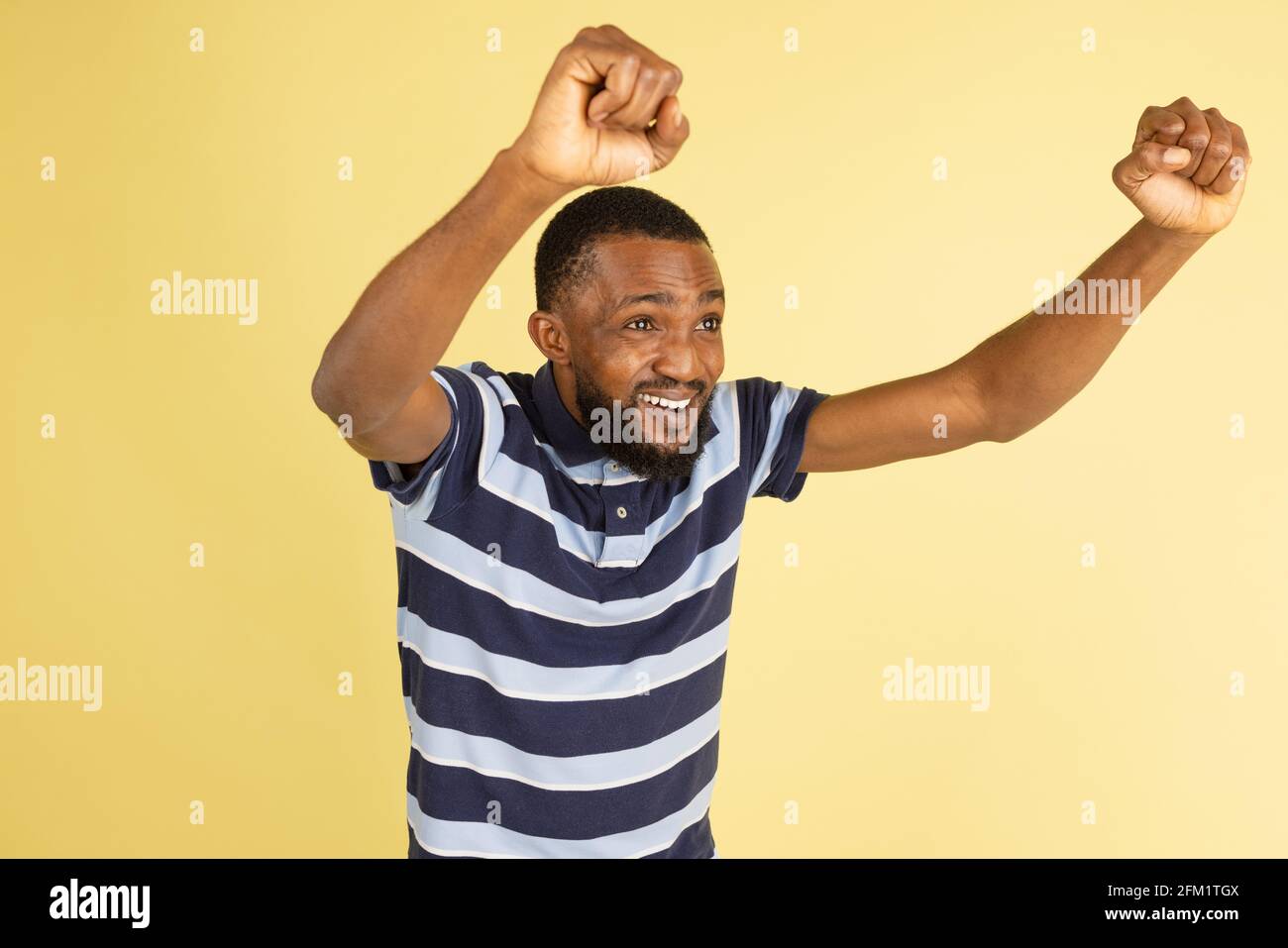 One African young man posing isolated over yellow studio background ...