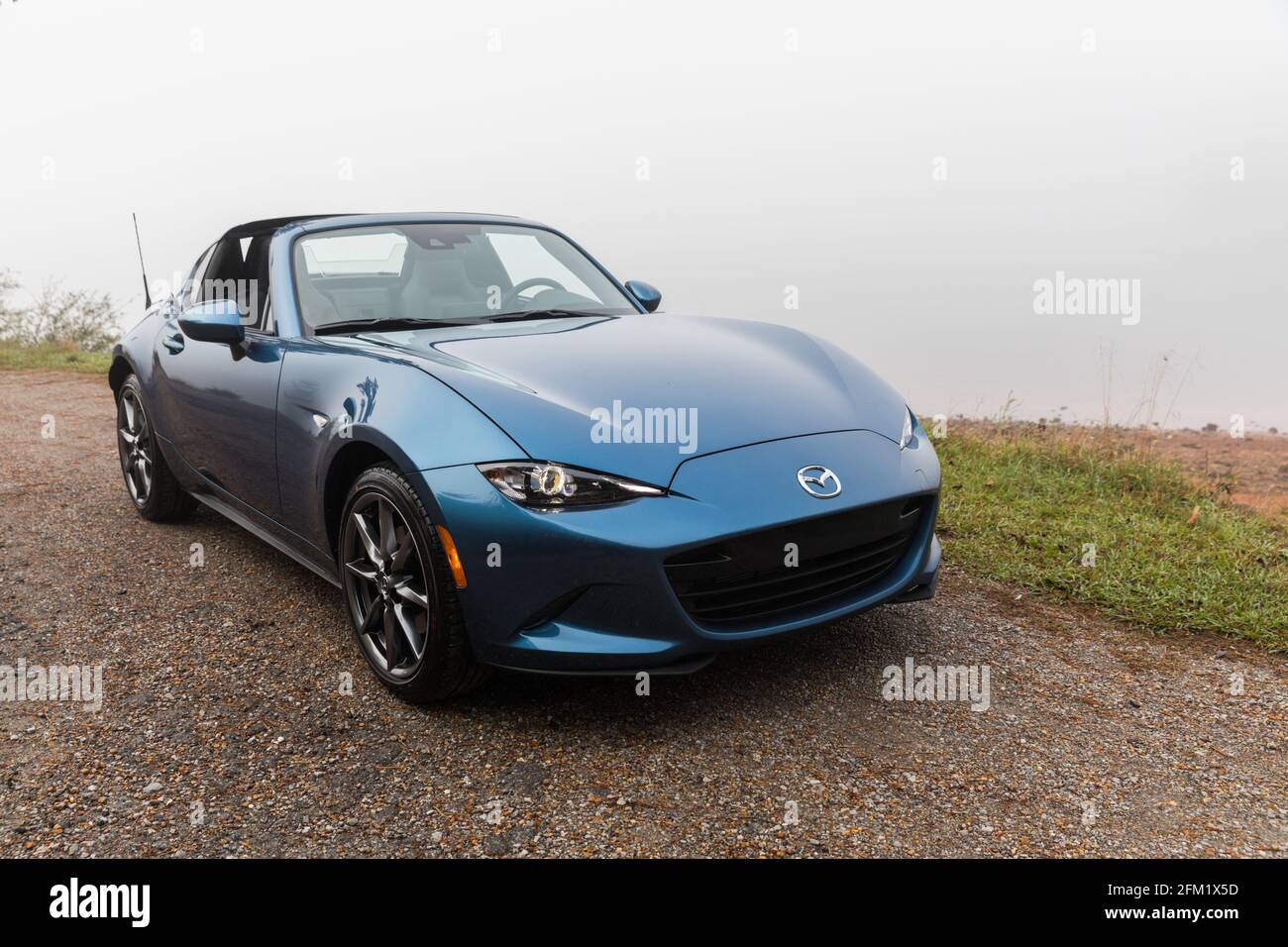 New blue 2020 Mazda MX-5 GT RF, parked (with the roof down) next to the ...