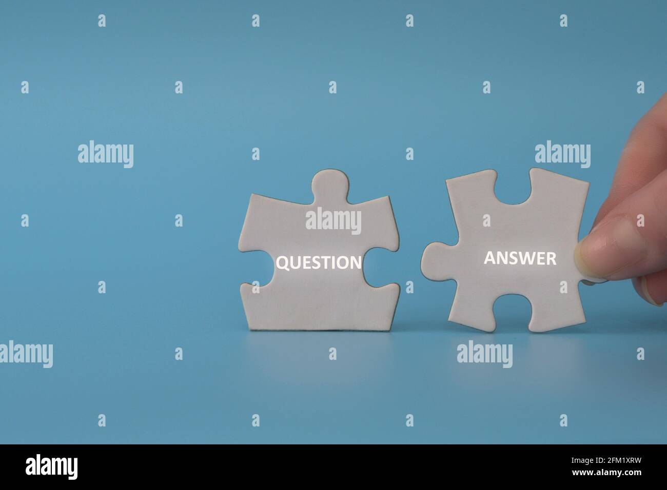 Hand holding piece of puzzle with word ANSWER and piece of puzzle with ...