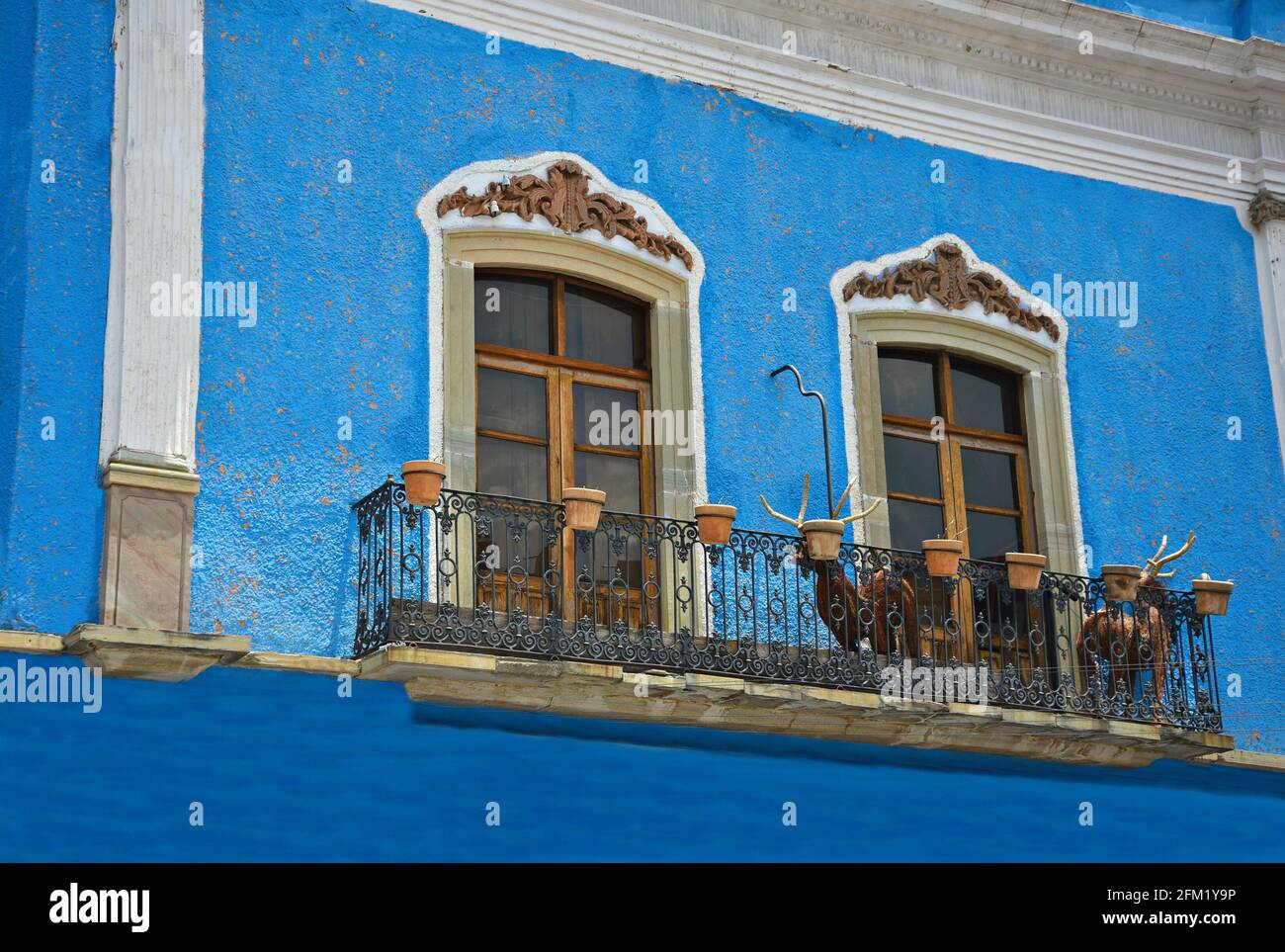 Spanish Colonial house with a Venetian blue stucco wall, stone trimmed ...