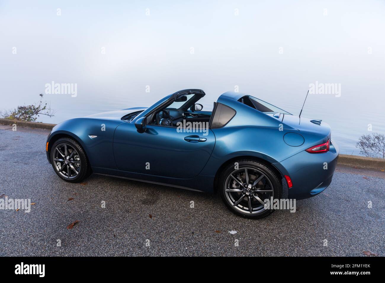New blue 2020 Mazda MX-5 GT RF, parked (with the roof down) next to the ...
