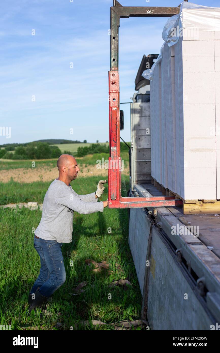 Unloading building blocks from a truck using a crane. Hydraulic ...