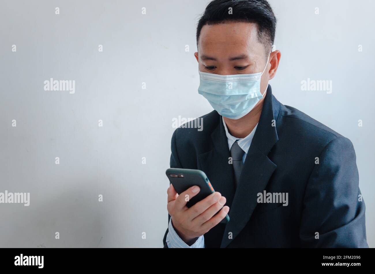 Business men wear face masks to watch mobile phones Stock Photo - Alamy