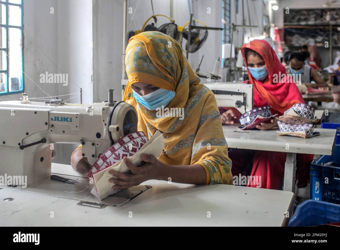 A worker wearing a face mask is seen making an Islamic Tupi (cap) at a ...