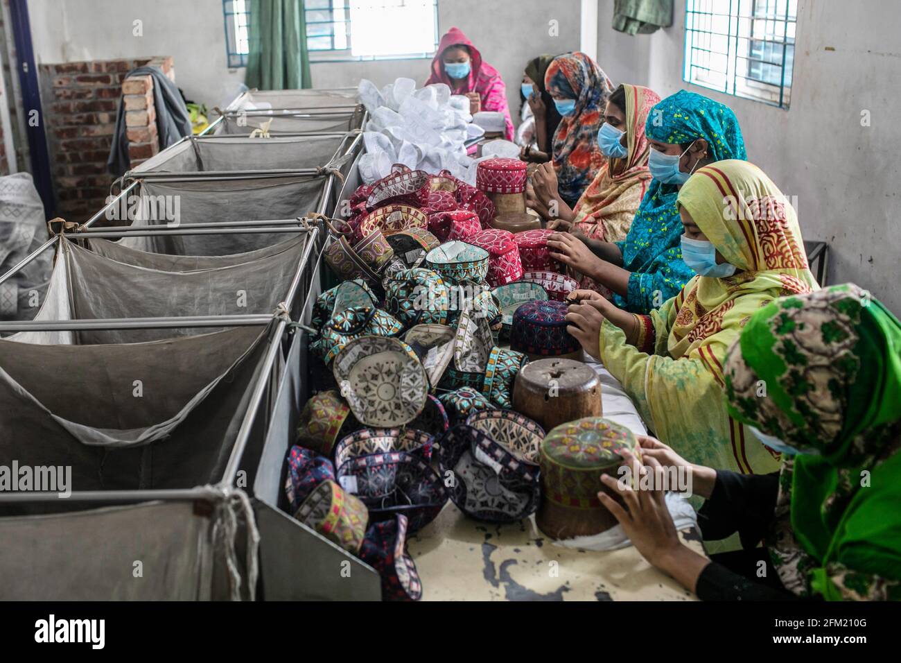A group of workers wearing masks are seen making Islamic Tupi (caps) at ...