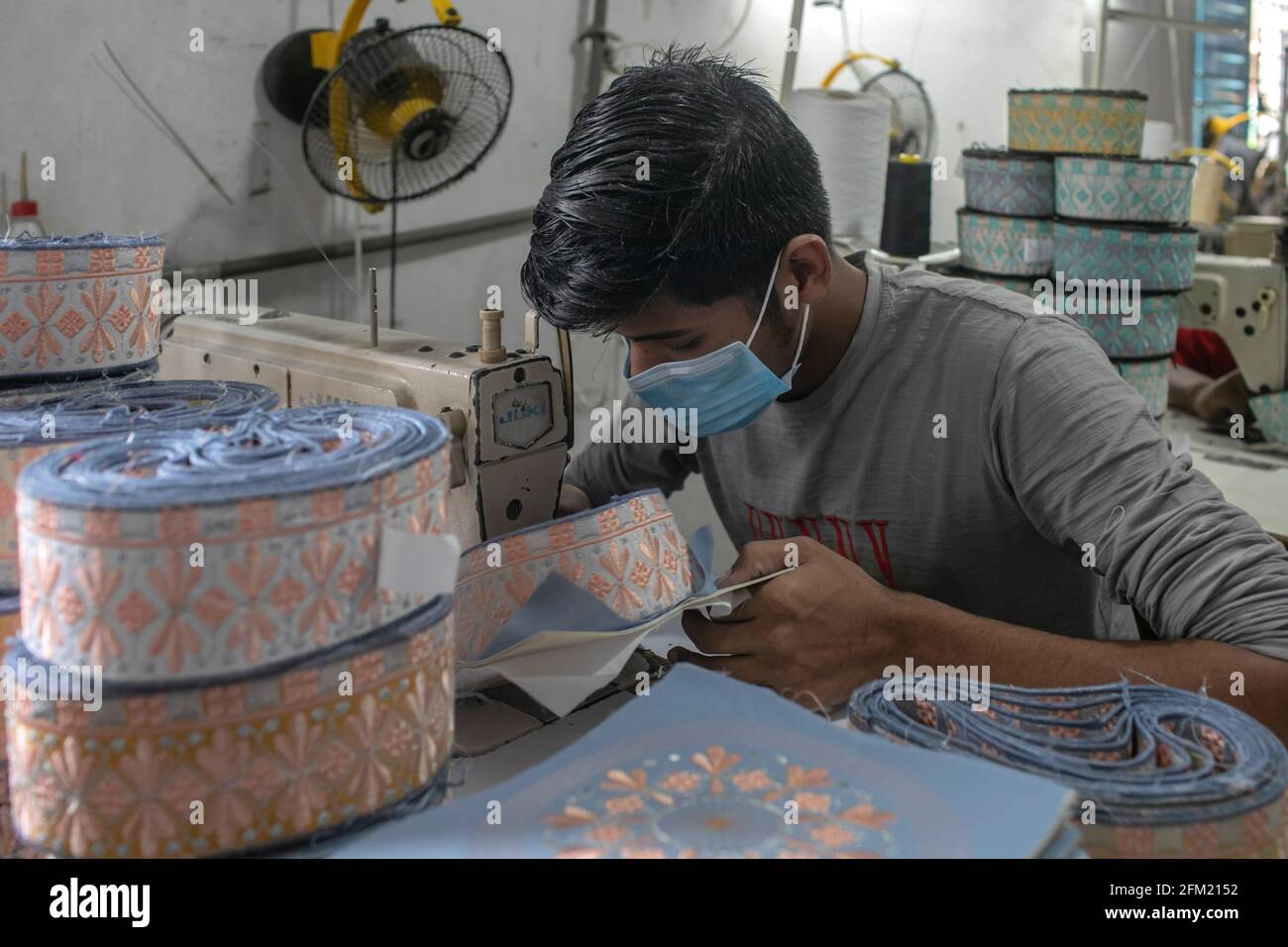A worker wearing a face mask is seen making an Islamic Tupi (cap) at a ...