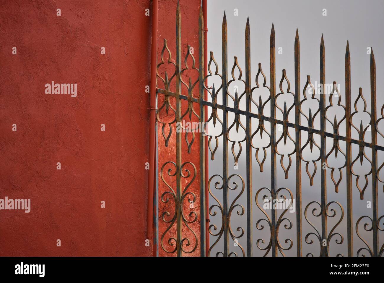 Handcrafted wrought iron balcony railing on a Venetian red stucco wall ...