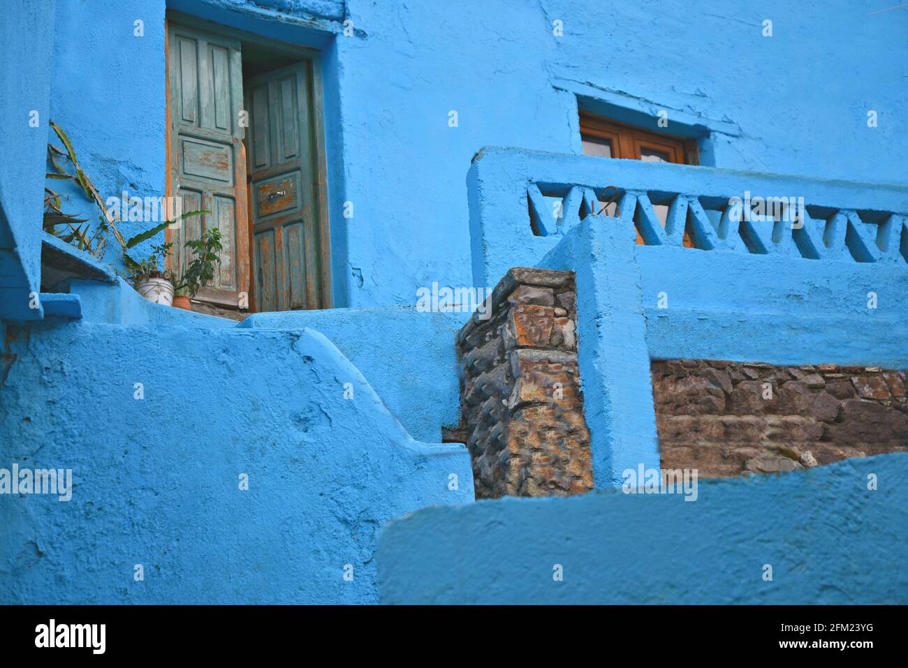 Adobe house facade with light blue walls, stone trim and an antique ...