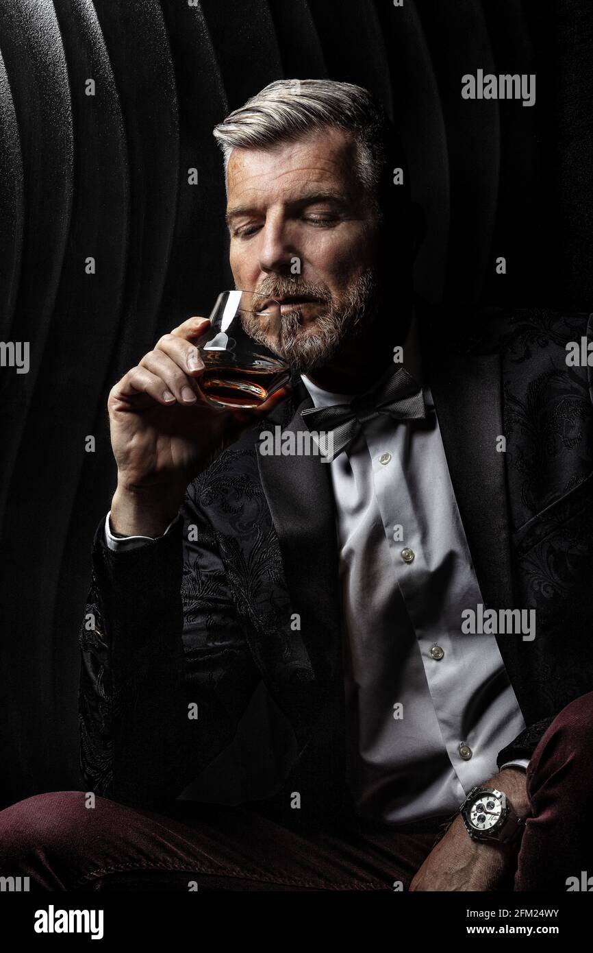 Portrait of a gentleman observing his glass of alcohol Stock Photo - Alamy