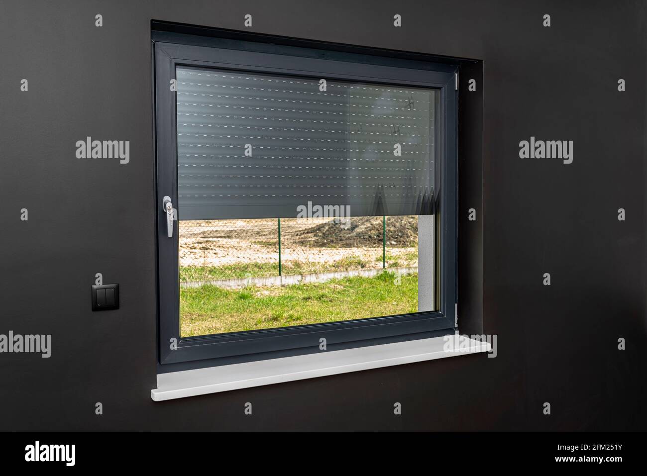 A large window in a room with black walls, half covered with external ...