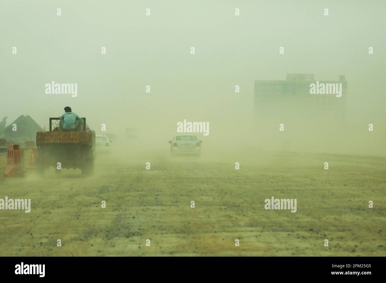 Vehicles crossing a dusty road.Dust pollution reaches an alarming stage ...