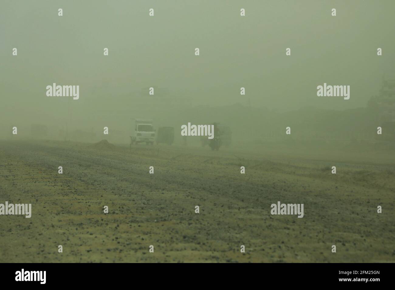 Vehicles and motorcycles crossing a dusty road. Dust pollution reaches ...