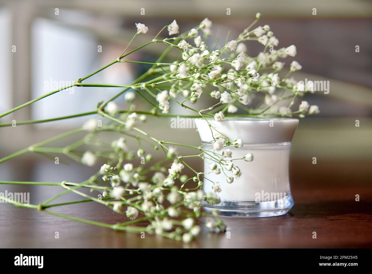 nutritious cream in glass jar and gypsophila flowers on table of makeup ...