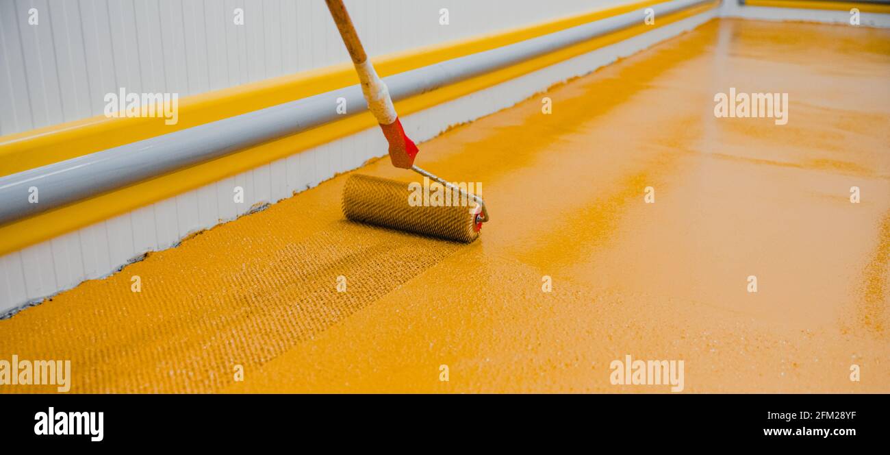 Worker applying epoxy and polyurethane flooring system.These easy-to ...