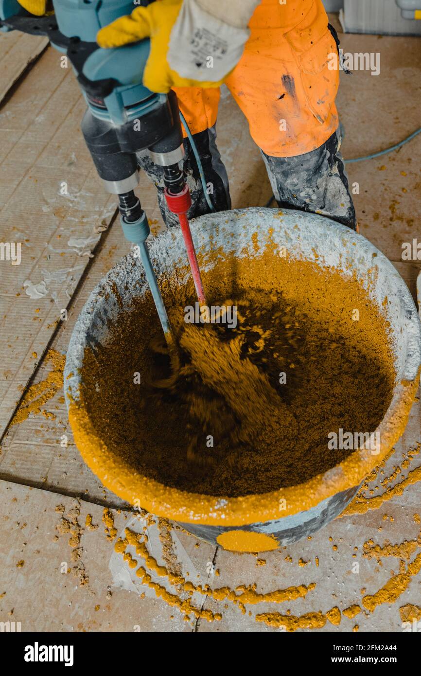 Photo in motion with a worker mixing colored polyurethane mortar with ...