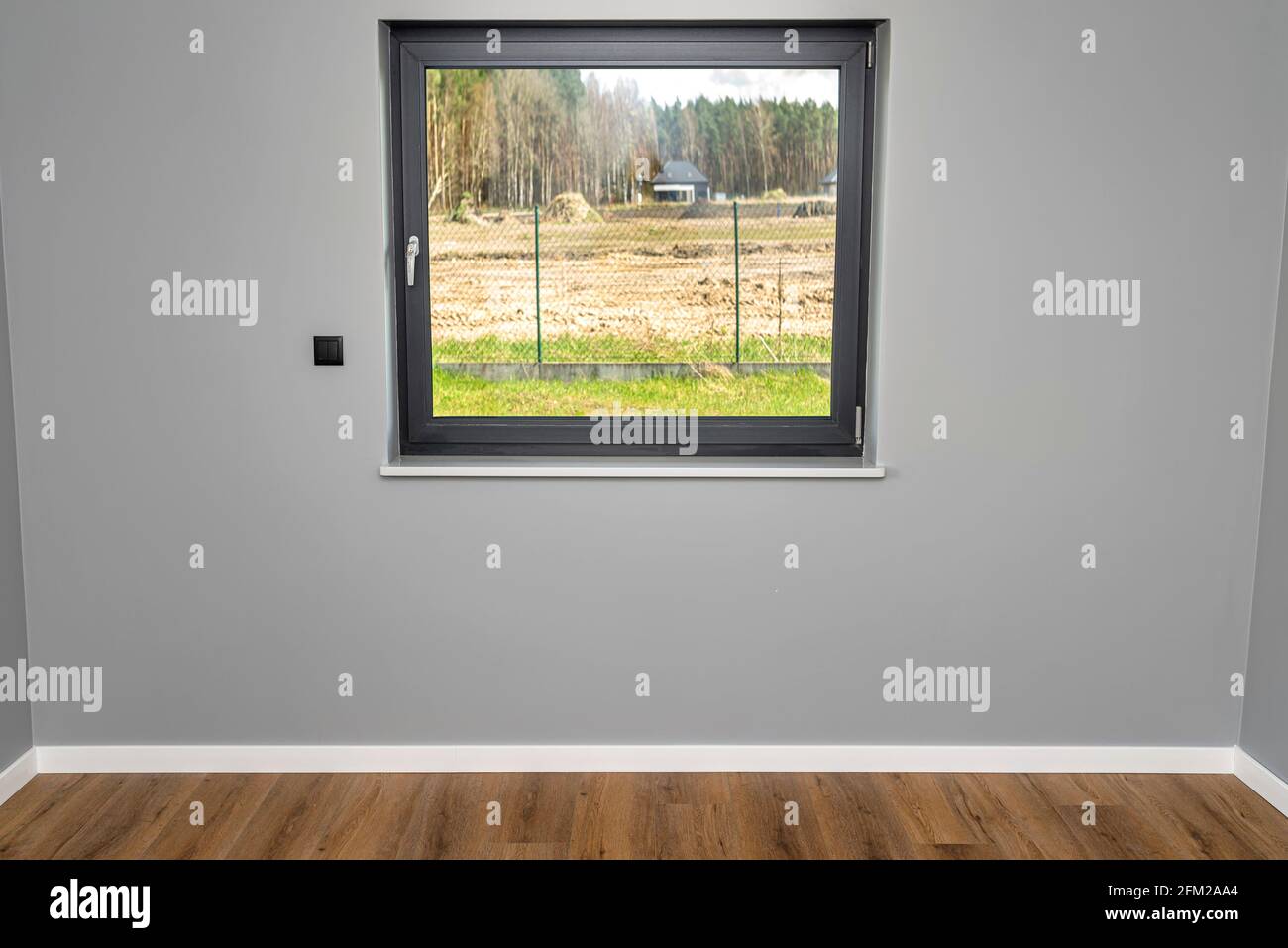 A large window in a room with gray walls and fully open roller shutters ...