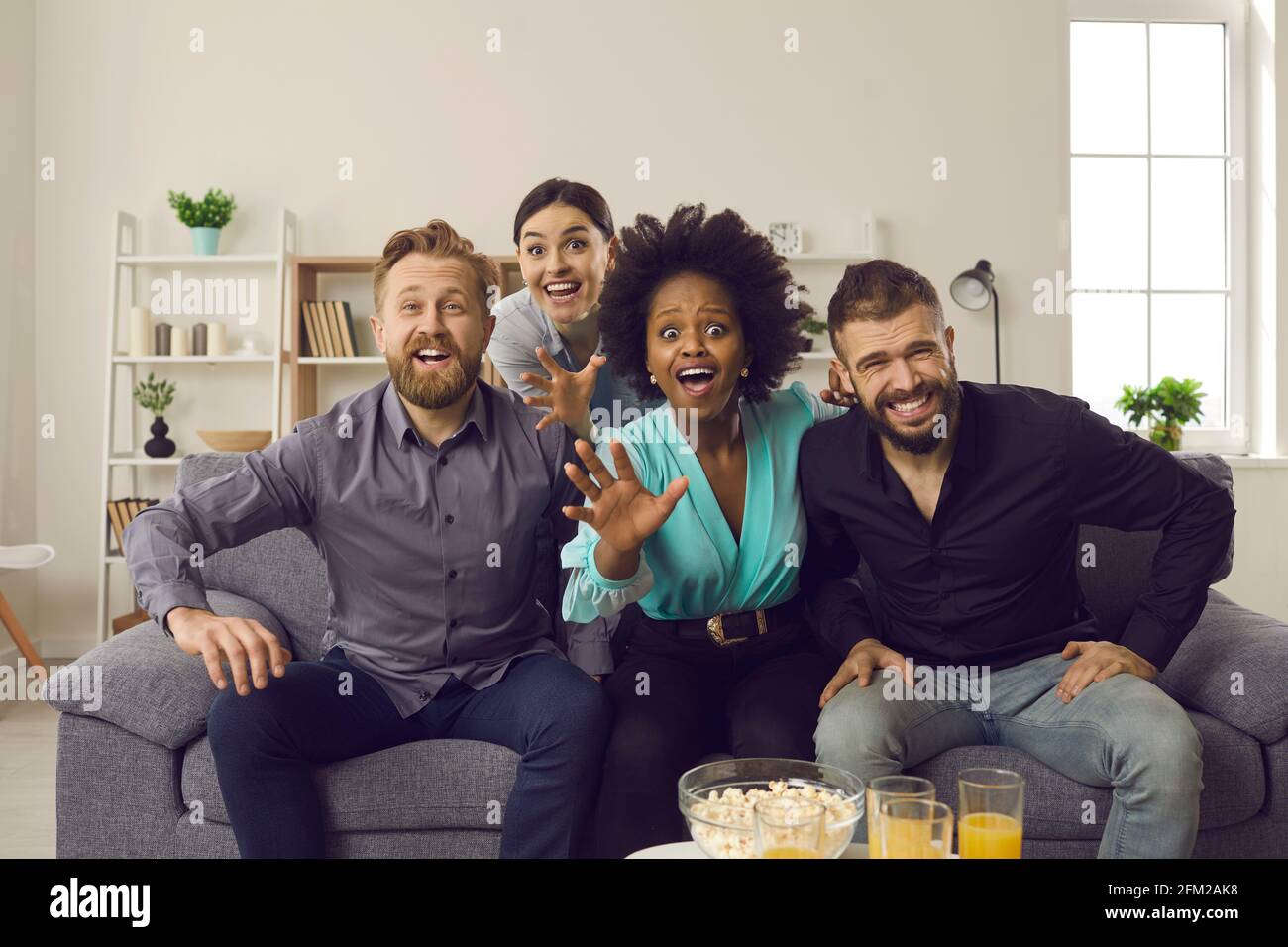 Group of scared international friends are sitting at home on the couch ...