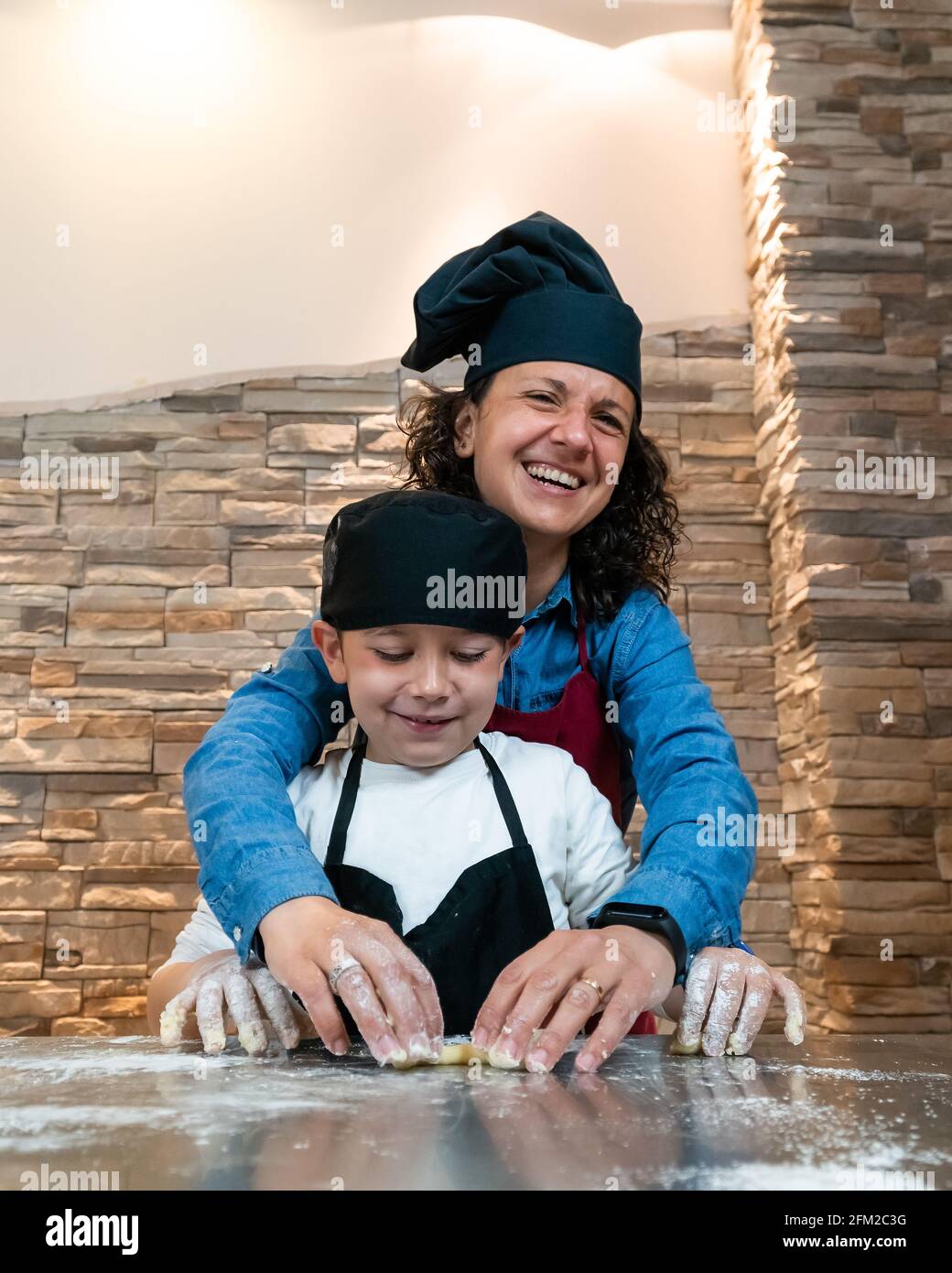 Mother and son cooking a pastry together in chef's costumes Stock Photo ...