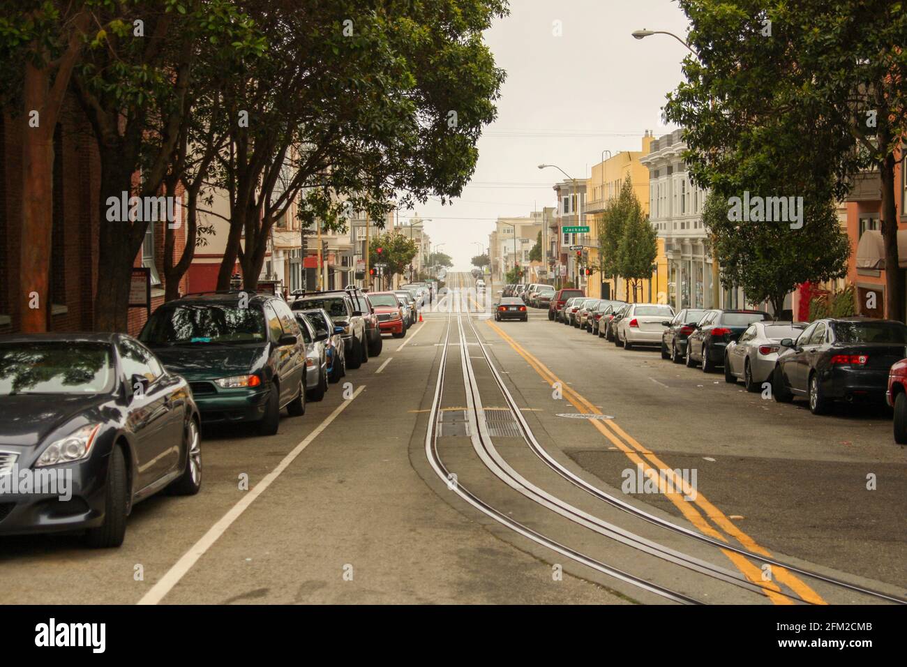 A straight and empty street in San Francisco with cars parked on both ...