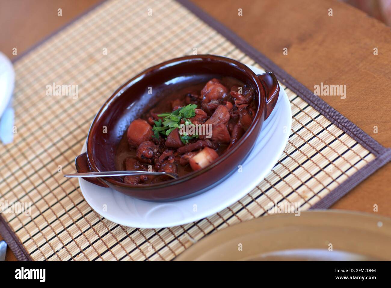 Octopus cooked in red wine in the greek restaurant Stock Photo - Alamy