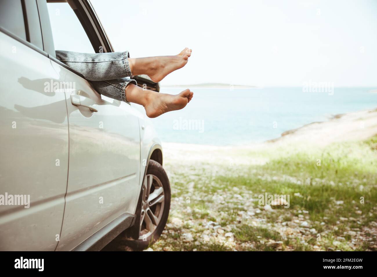 woman legs stick out from car window sea beach on background. summer ...
