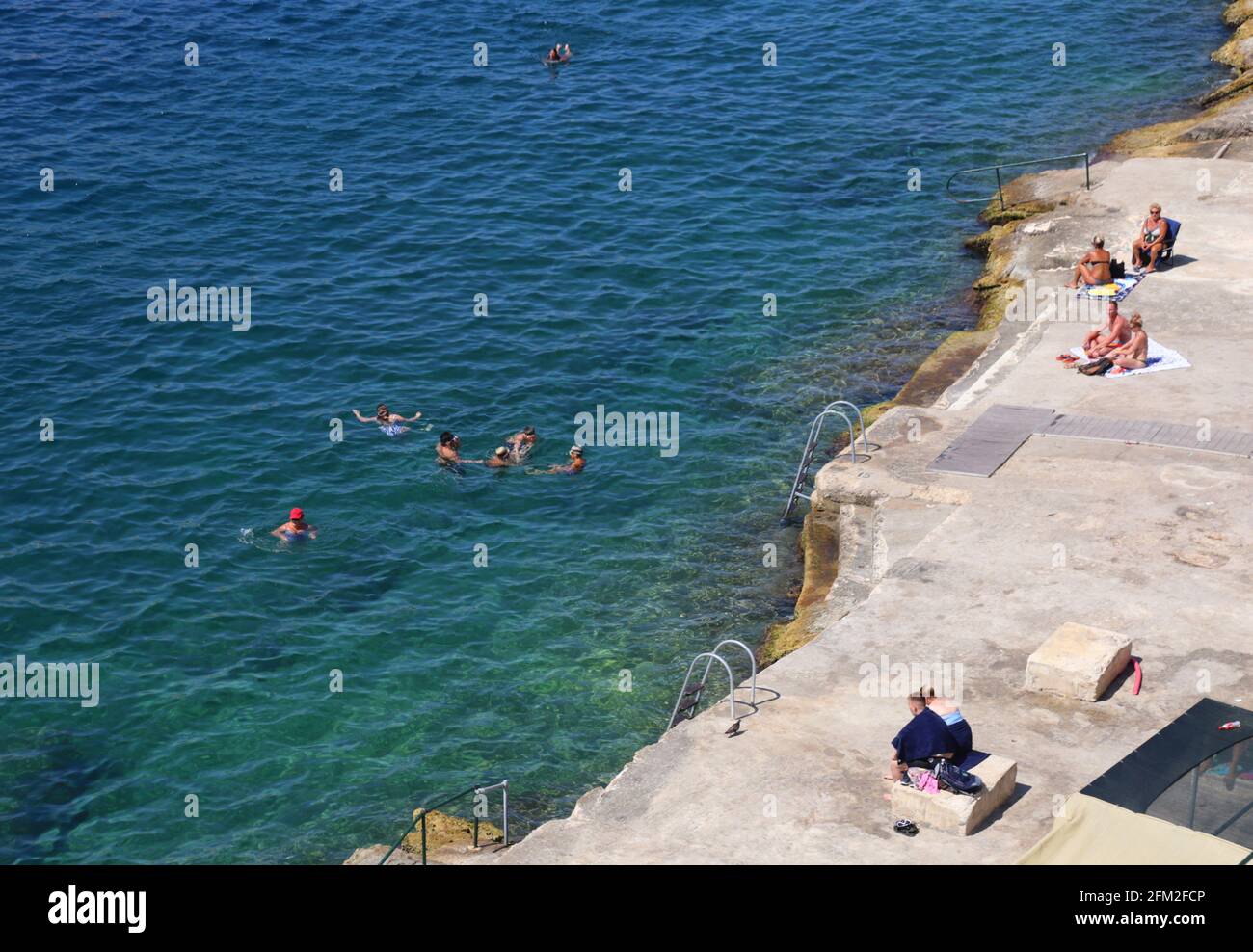 Valletta. Malta. People sunbathing and swimming in the sea at ...