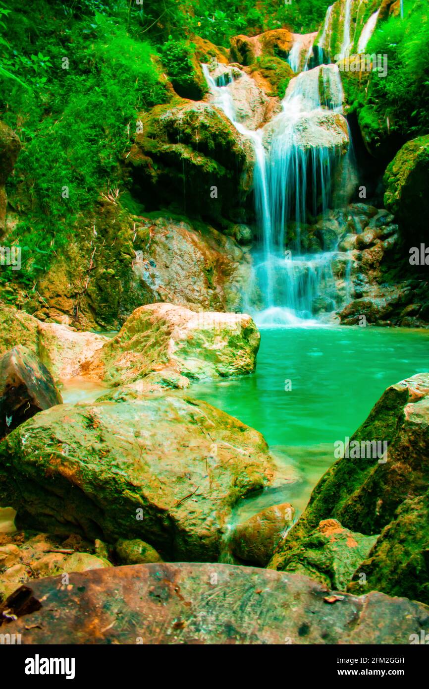 A waterfall flowing over rocks into a river or lake with turquoise ...