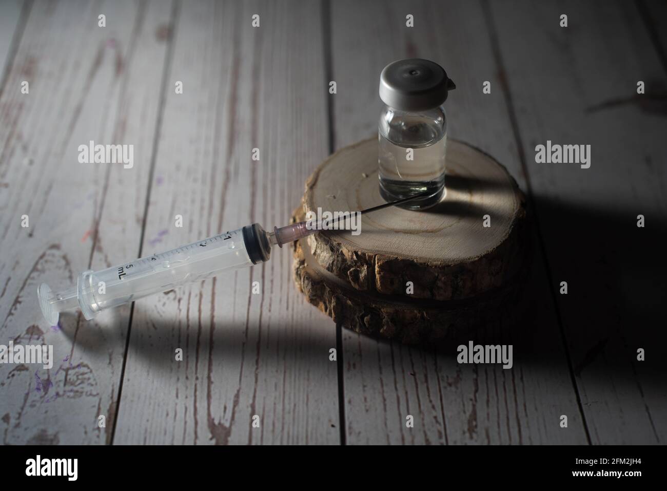 syringe pointing upwards with glass vial filled with liquid serum ...