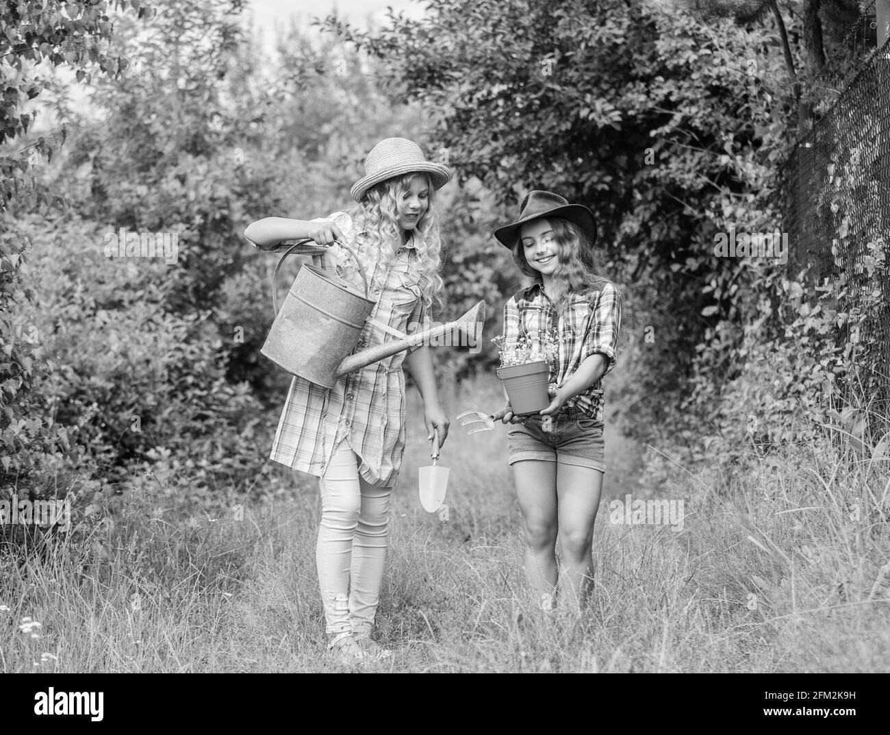 Girls in hats planting plants. Rustic children nature background ...