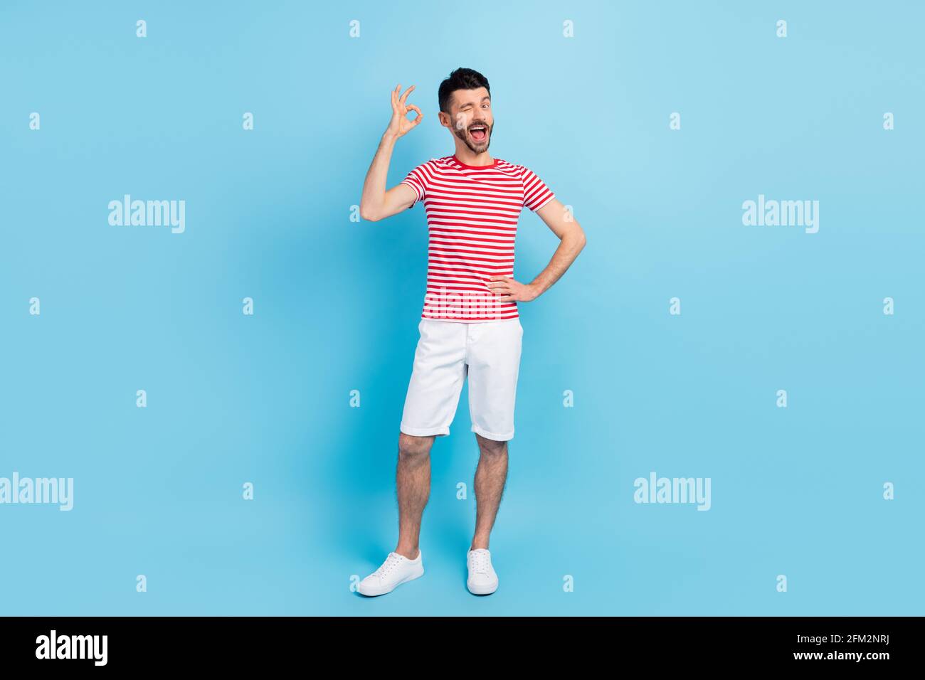 Full body photo of charming handsome young guy wink show okay sign ad ...