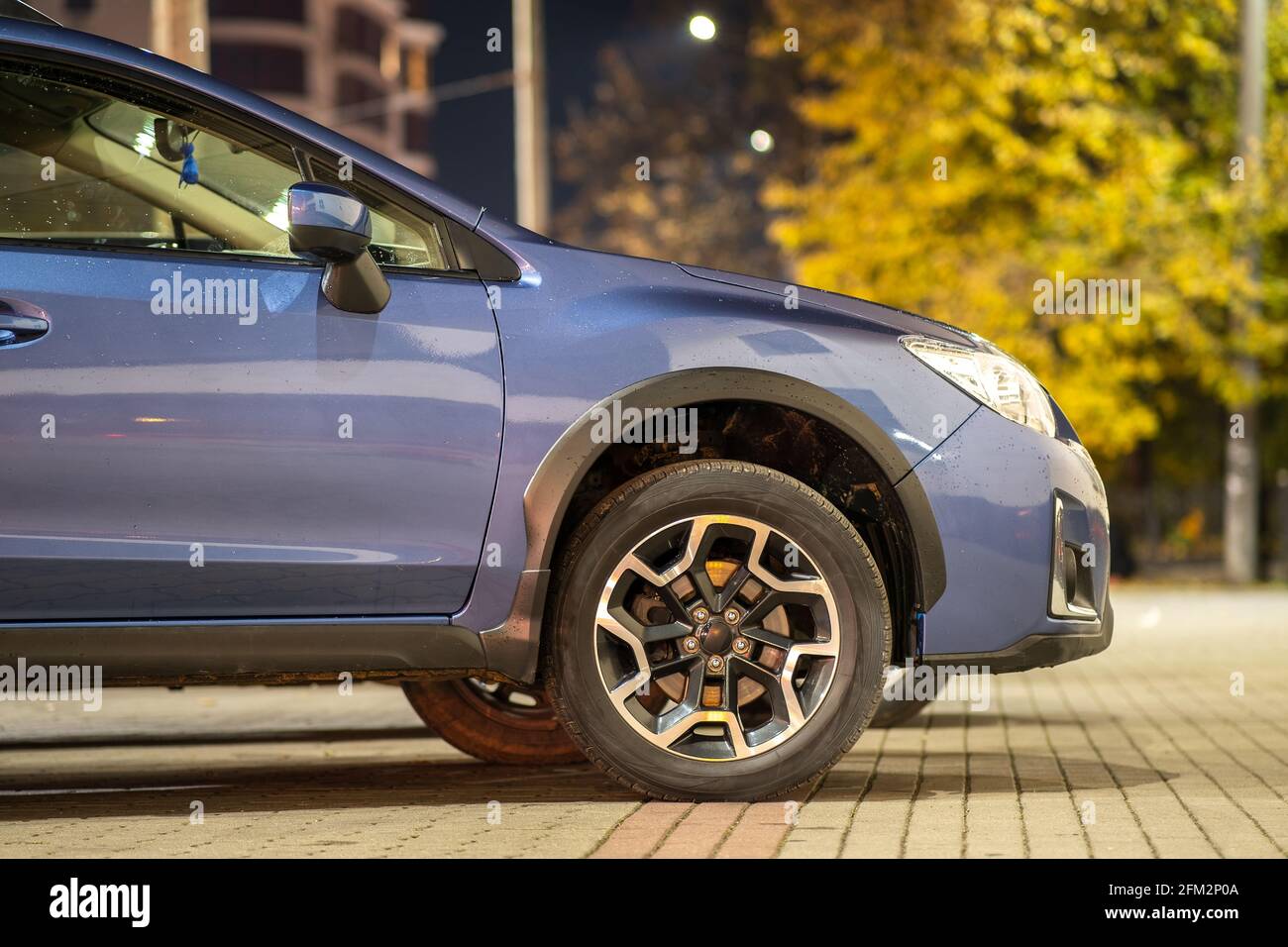 Blue car parked on brightly illuminated city street at night Stock ...