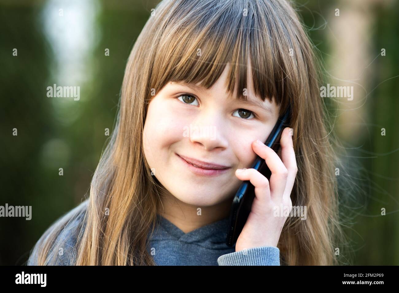 Portrait of pretty child girl with long hair talking on cell phone ...
