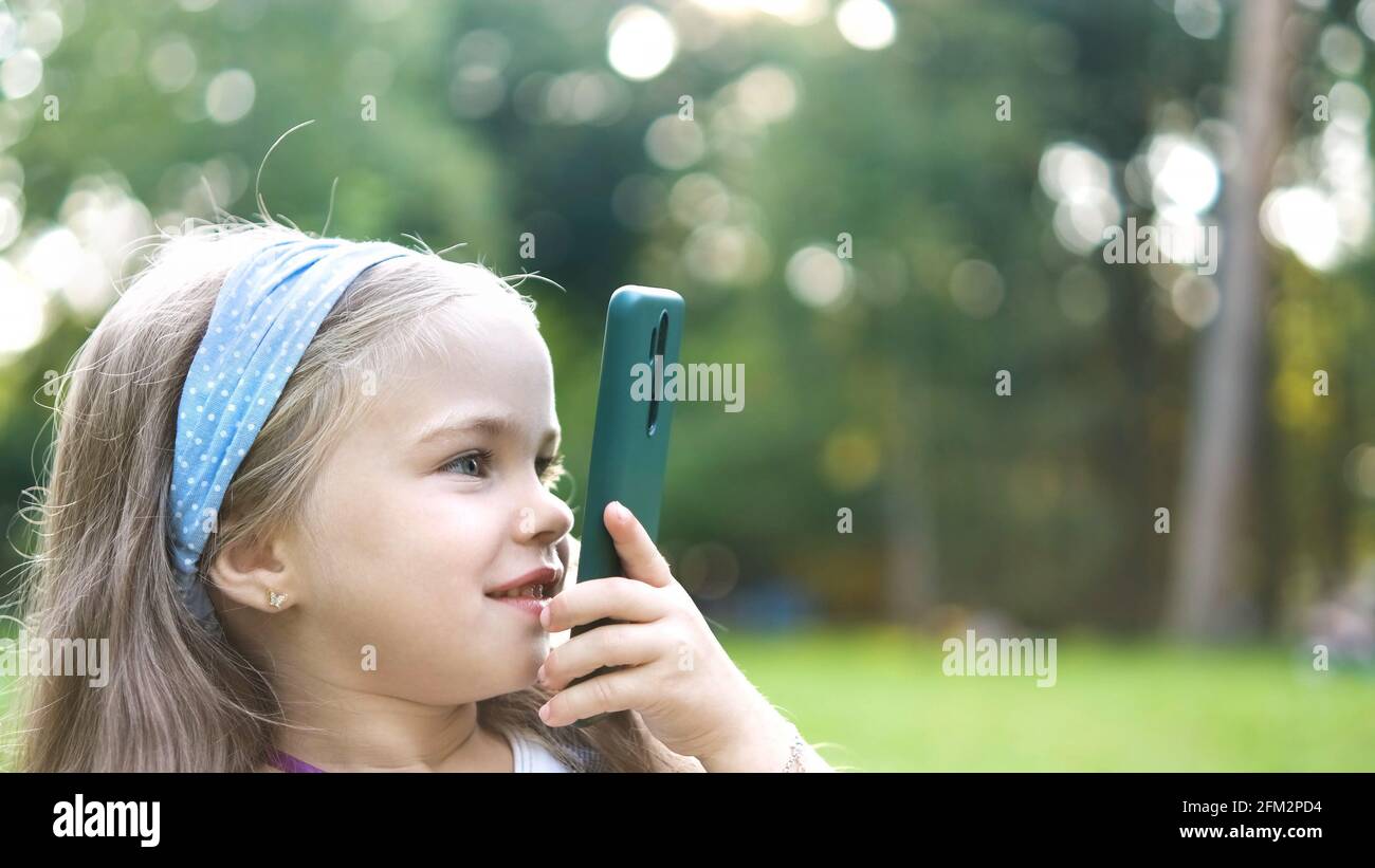 Happy little child girl having conversation talking on her sellphone in ...
