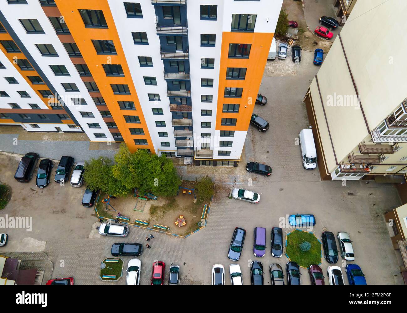 Aerial view of parked cars on parking lot between high apartment ...