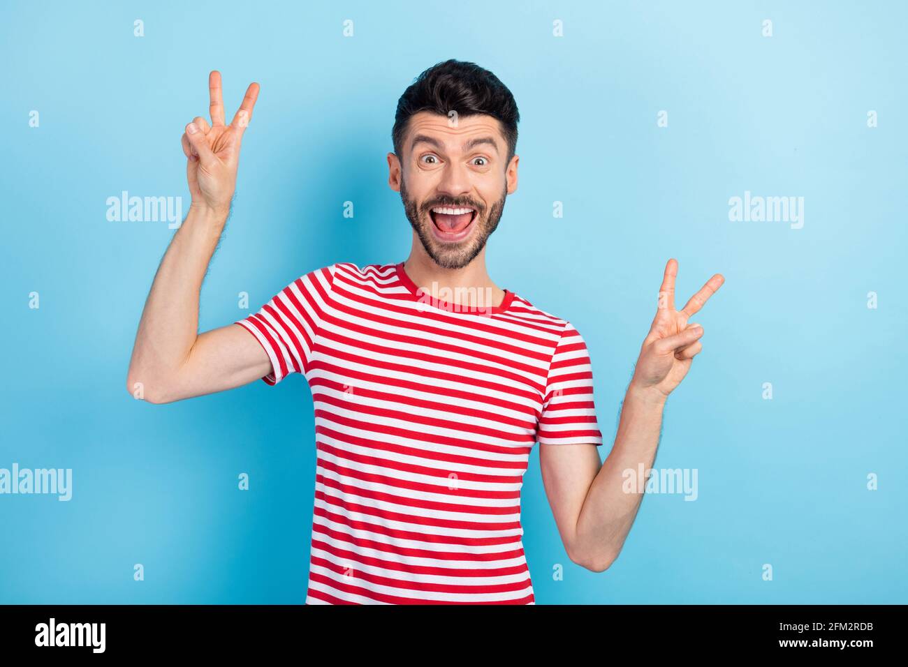 Photo of attractive positive cool guy raise hands make v-signs peace ...