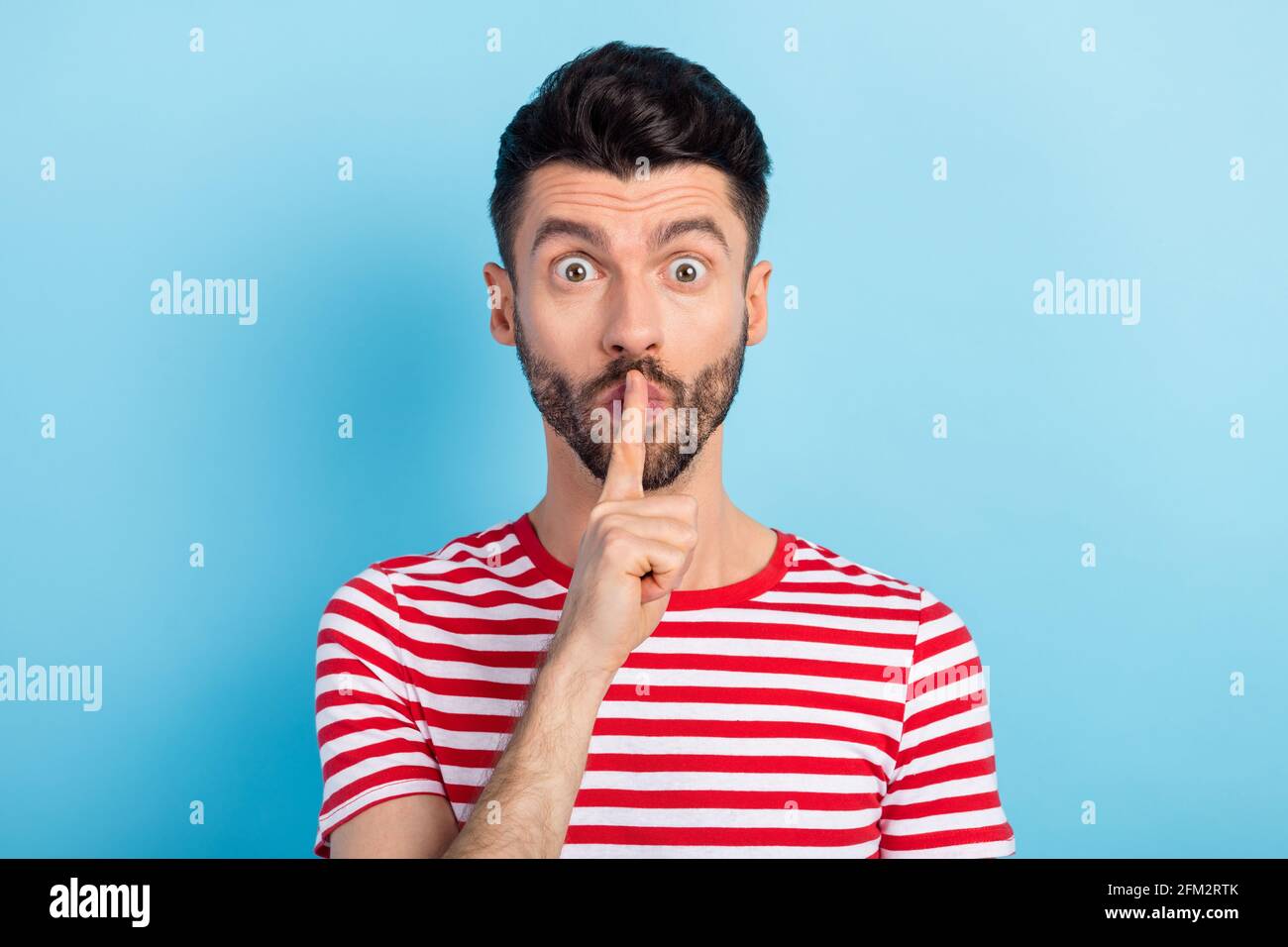Photo of pretty impressed young man dressed striped t-shirt finger lips ...