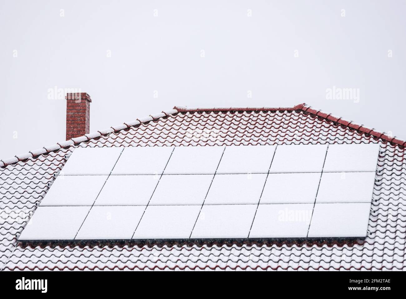 Completely snow-covered house roof with photovoltaic solar panels in ...