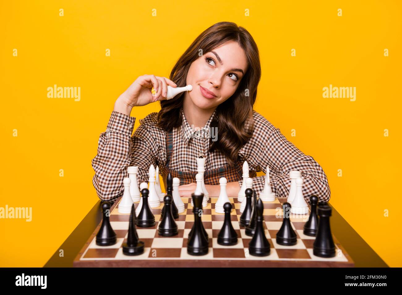 Photo of optimistic nice brunette lady sit play chess hold piece look ...