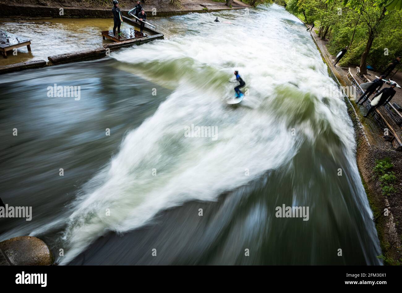 Munich, Germany. 05th May, 2021. Surfers ride the Eisbach wave near ...
