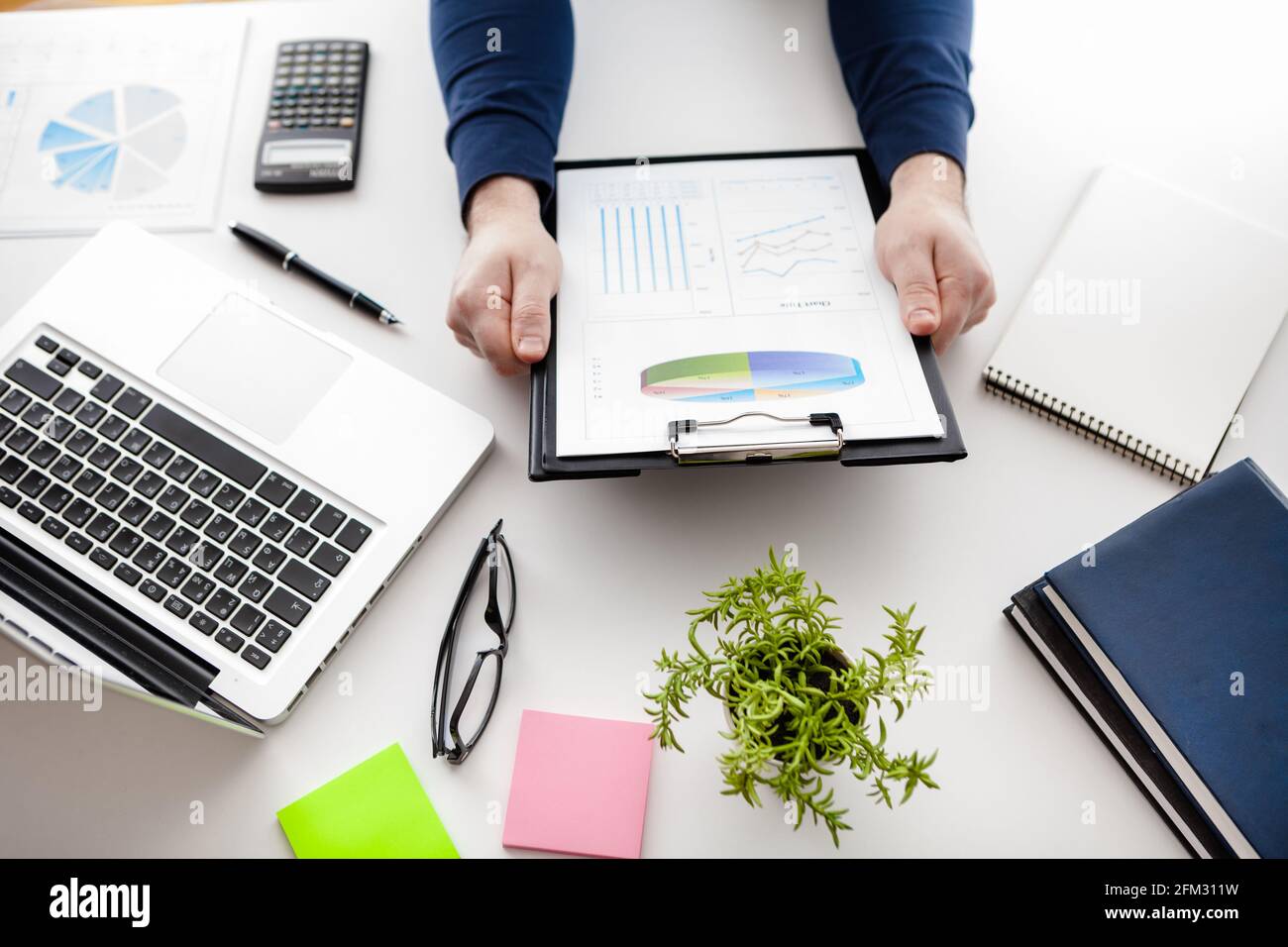 Businessman holding a pen is working with graph documents and sunset ...