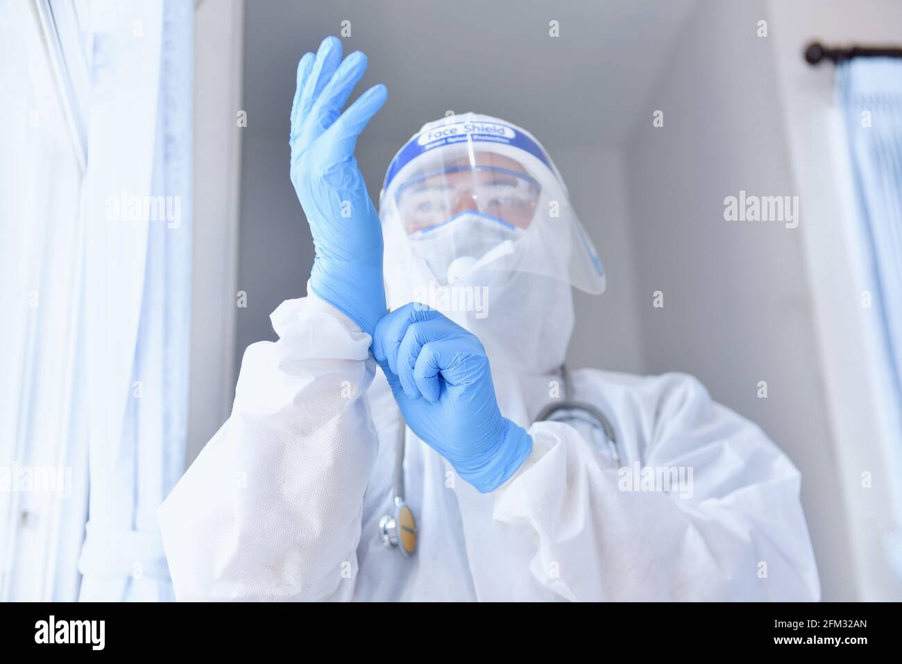 Doctor wearing PPE putting on surgical gloves, Thailand Stock Photo - Alamy