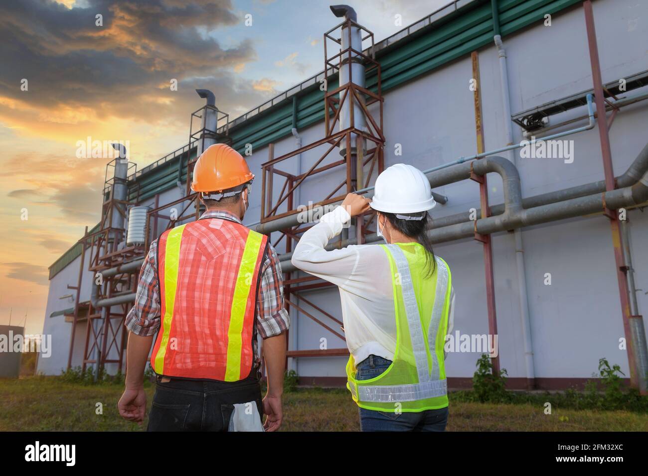 Two engineers looking at construction plans in front of a factory ...